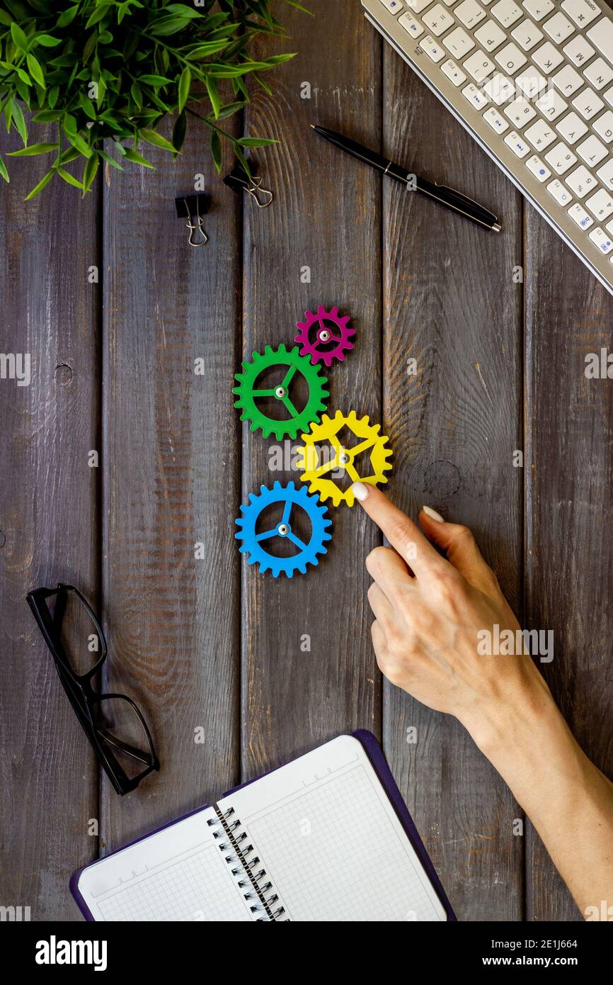 Hand puts a gear into one working mechanism. Teamwork and collaboration ...