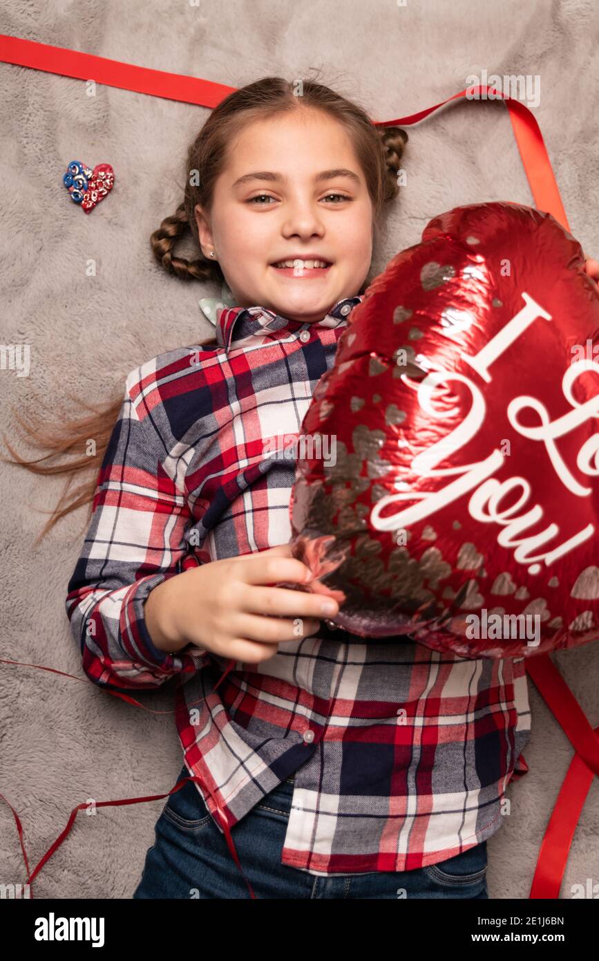 cute smiling girl holding red heart shaped balloon. Caucasian beautiful ...