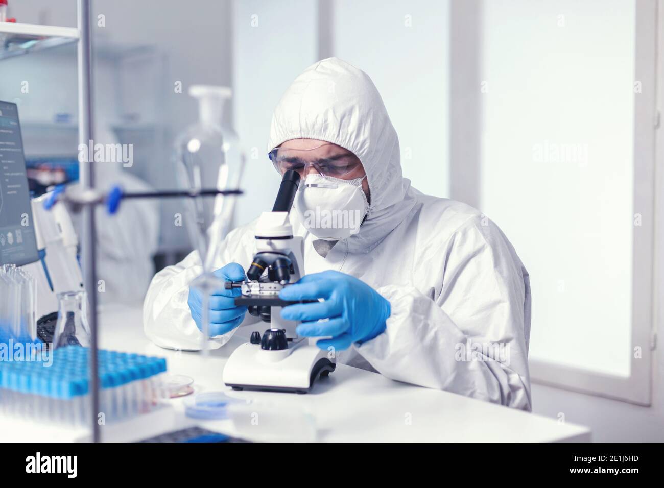 Microbiologist examining virus evolution using high tech microscope ...