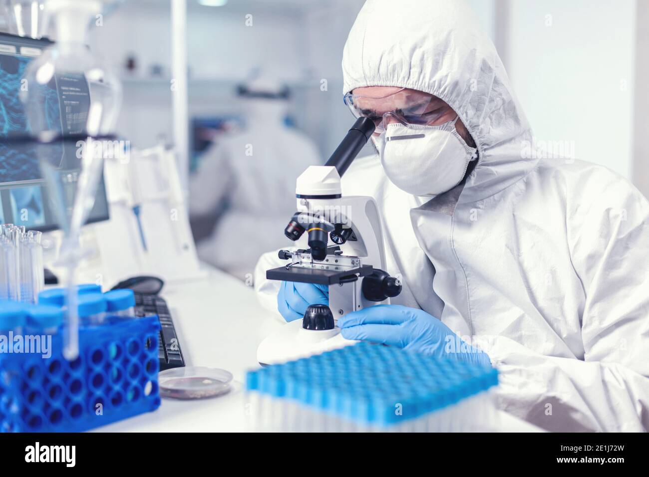 Focused healthcare researcher with face mask and ppe analysing covid ...
