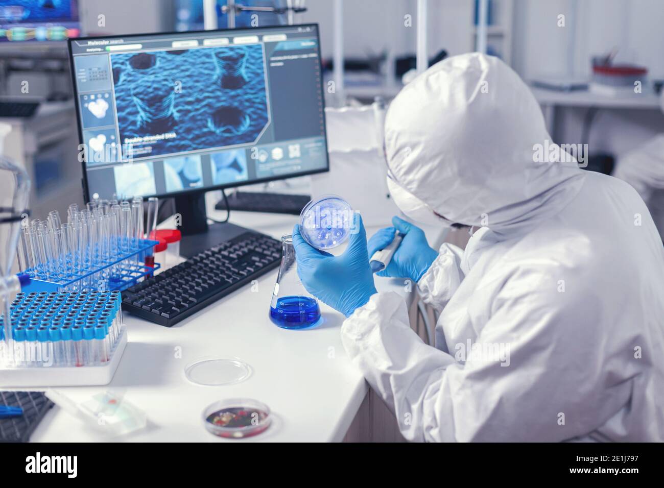 Scientific man in chemistry lab holding petri dish with virus sample ...