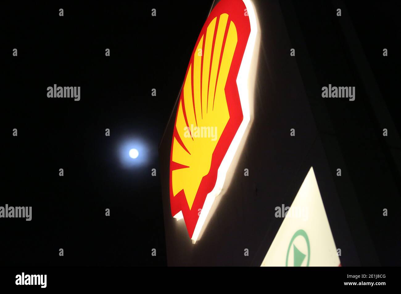 Illuminated Shell sign at night with full moon in the photo. Dark ...