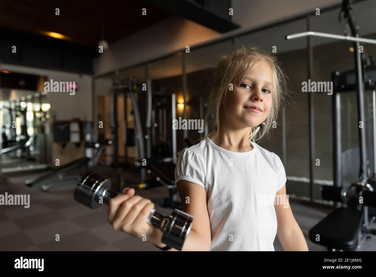 Little cute adorable caucasian blond girl doing finess exercise lifting ...