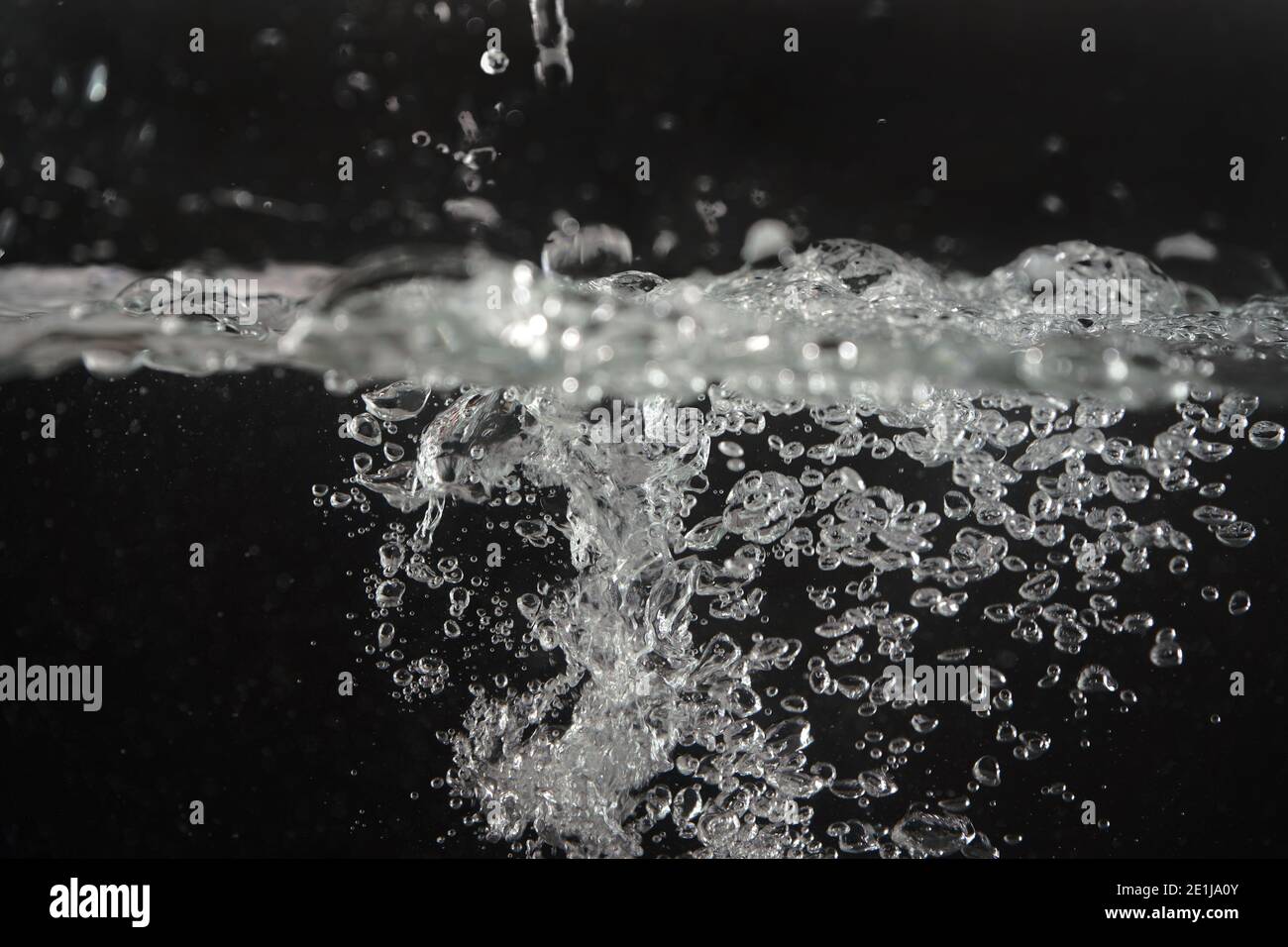 Water splashing as it's poured into aquarium tank, black background ...