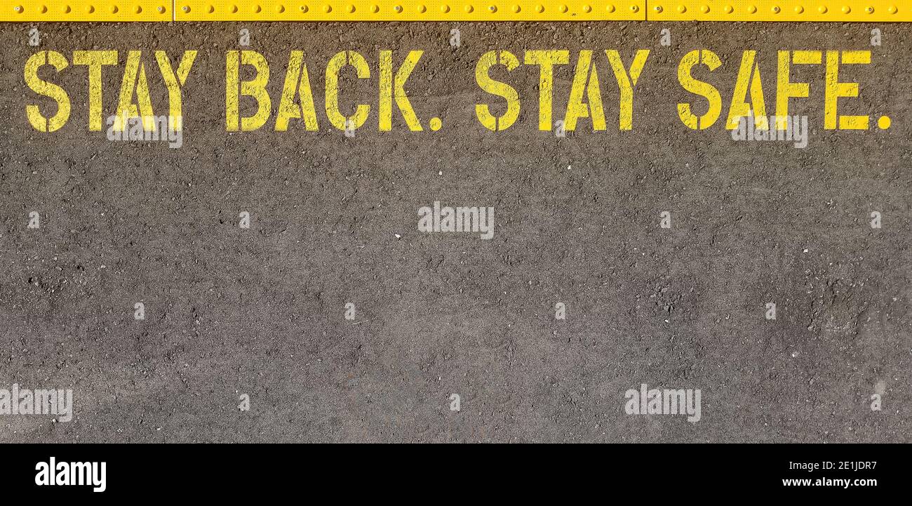 yellow sign at train station asking people to stay back, stay safe, on ...