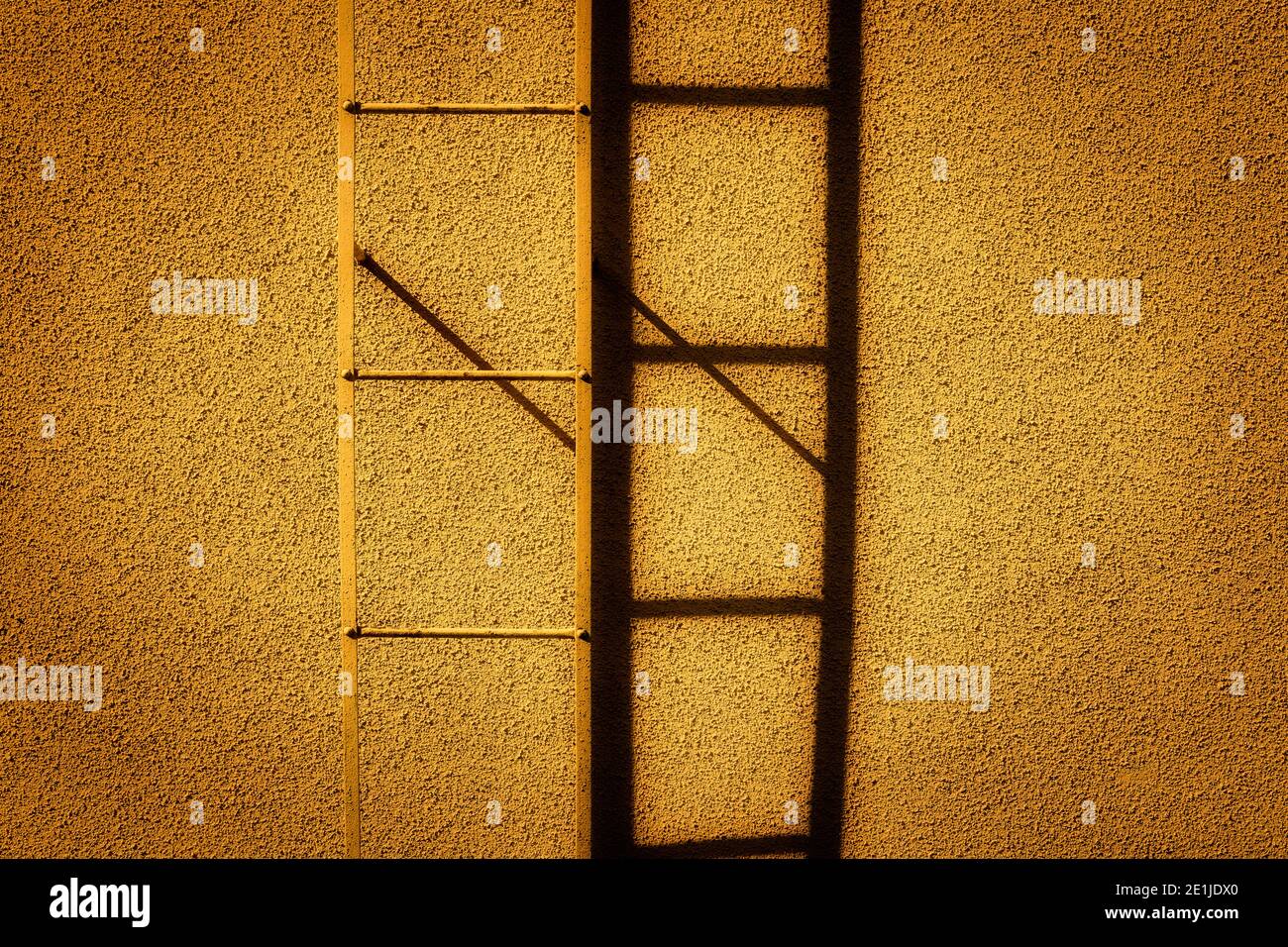 The ladder and its shadow by a yellow building Stock Photo - Alamy