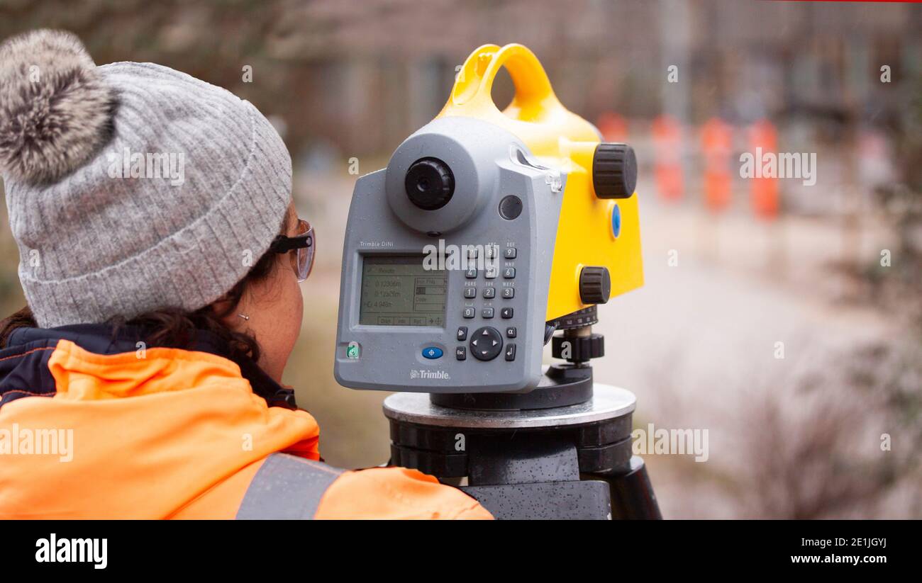 Female land surveyor operating a digital precision measurement level to ...