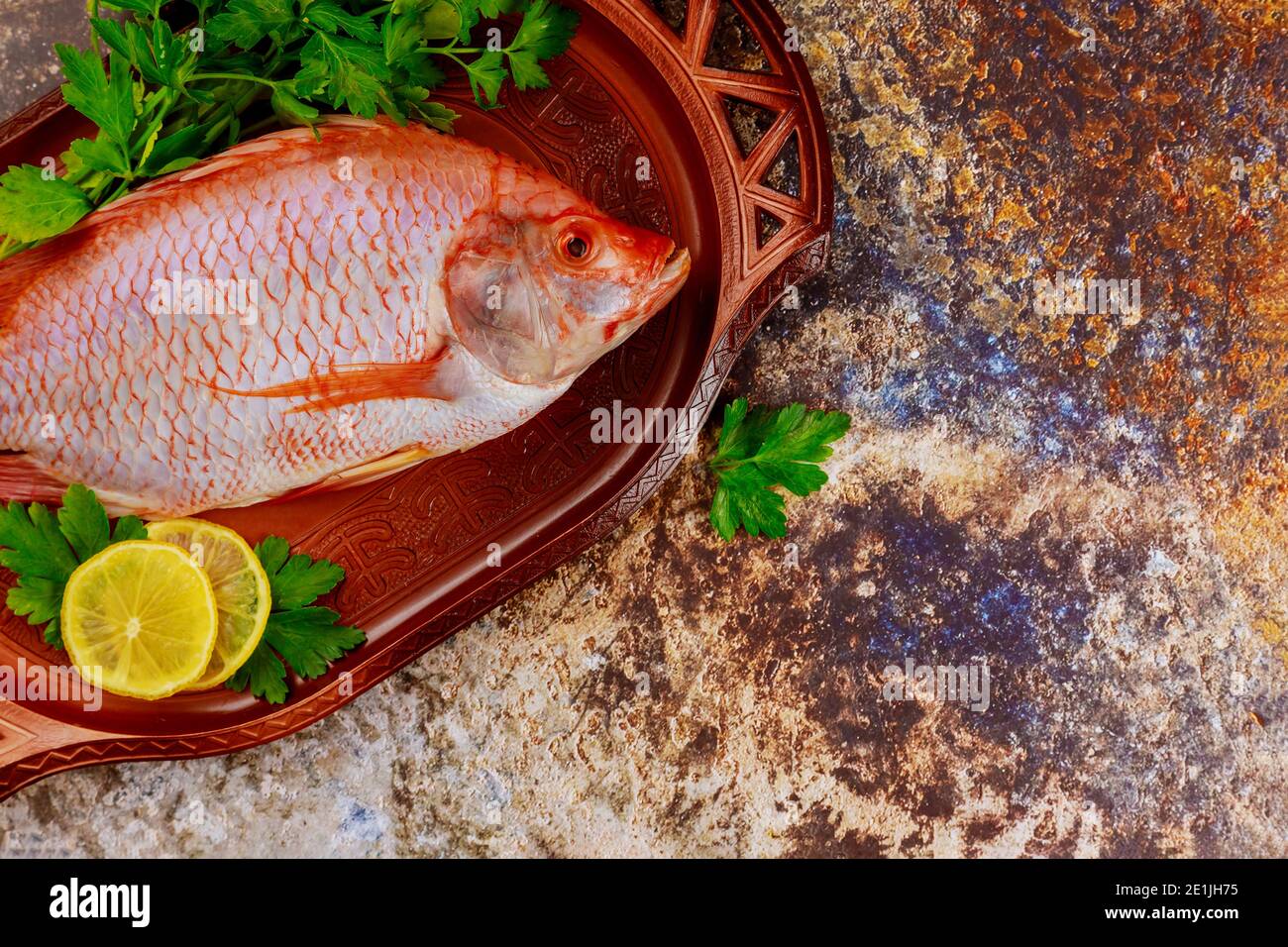 Pink raw tilapia fish with herbs and lemon. Top view Stock Photo - Alamy