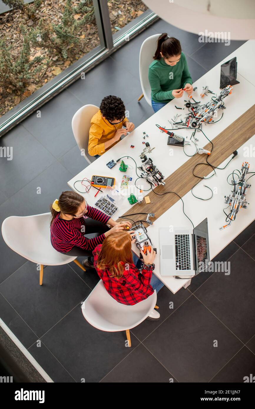 Overhead view at group of happy kids programming electric toys and ...