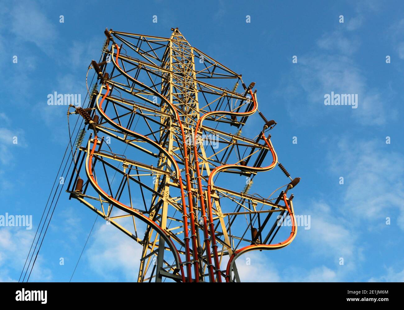 Electricity pylon with overhead cables in sunshine against a blue sky ...