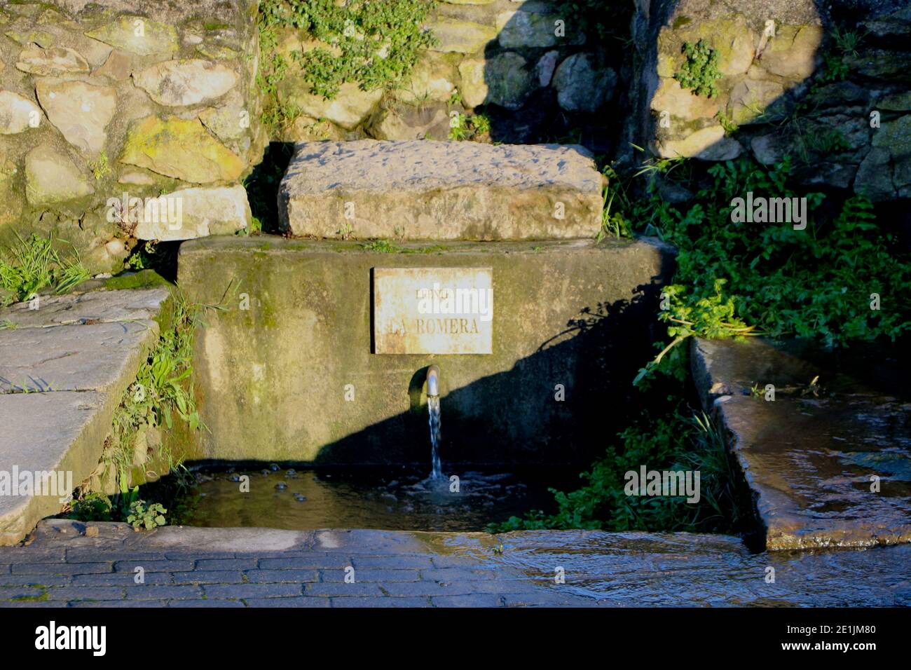 Pipe channelling untreated spring water into a trough by a roadside in ...