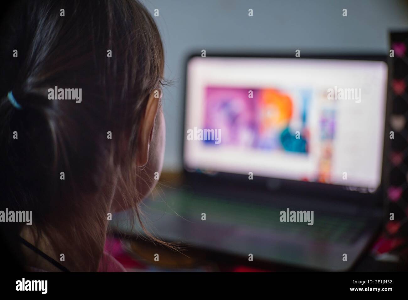 girl child in her bedroom using laptop computer and watching videos ...
