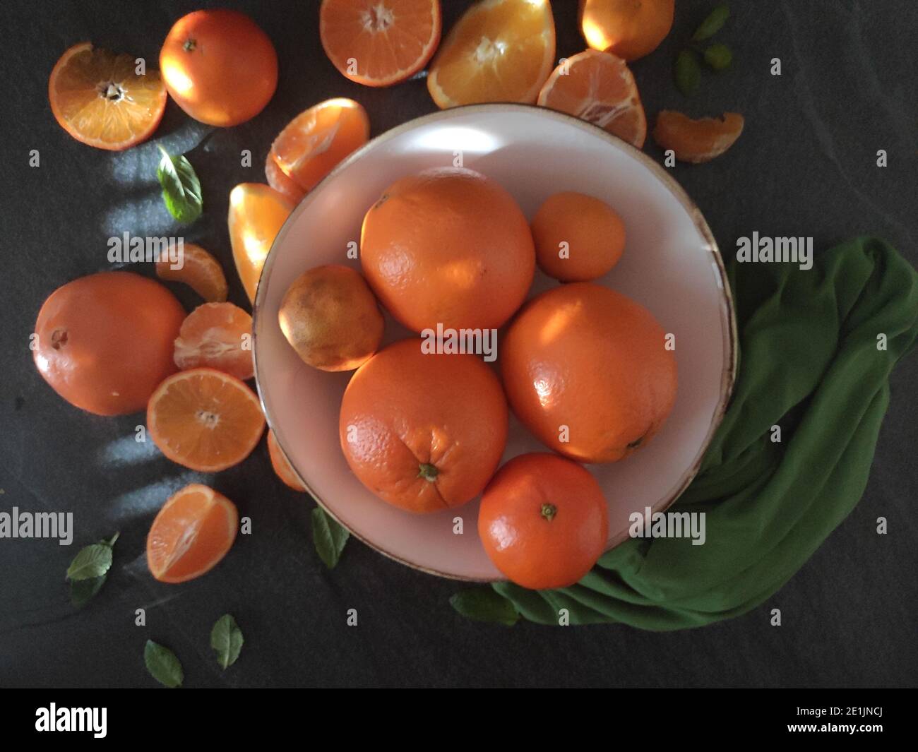 Whole and sliced oranges on a luxury dark background under the sunlight ...