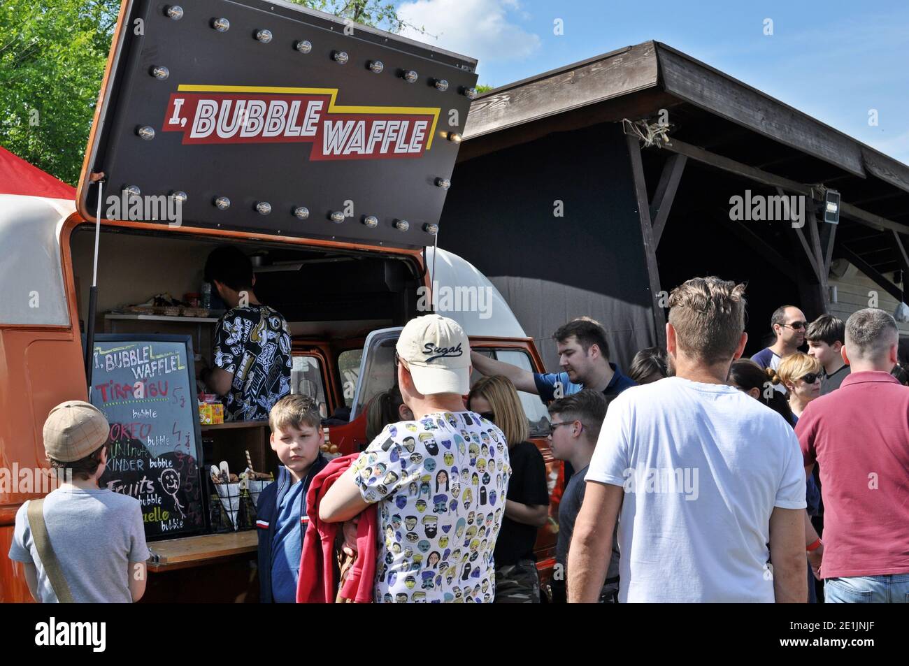 People standing in line in front of a auto stall at burger festival ...
