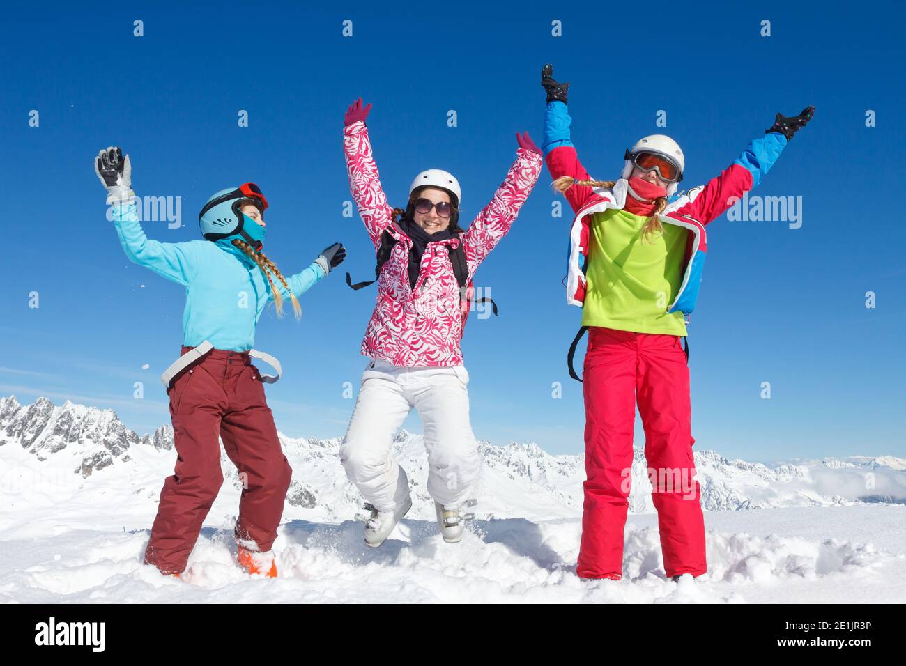 Three happy young girls on winter vacation in the mountain jumps in the ...