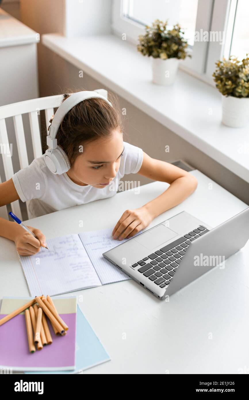 Top view of a teenager girl doing homework at home in front of a laptop ...