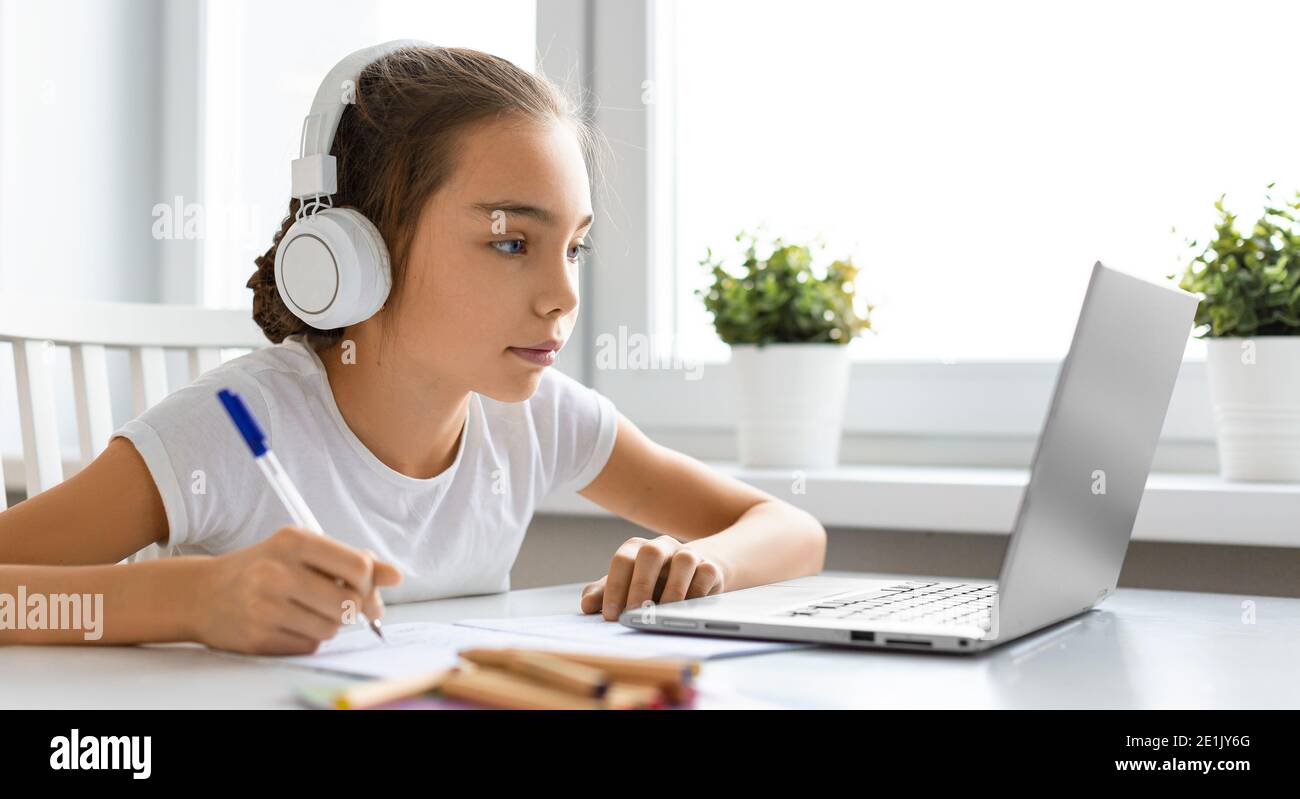 Teenager girl doing homework at home. She is looking at the laptop ...