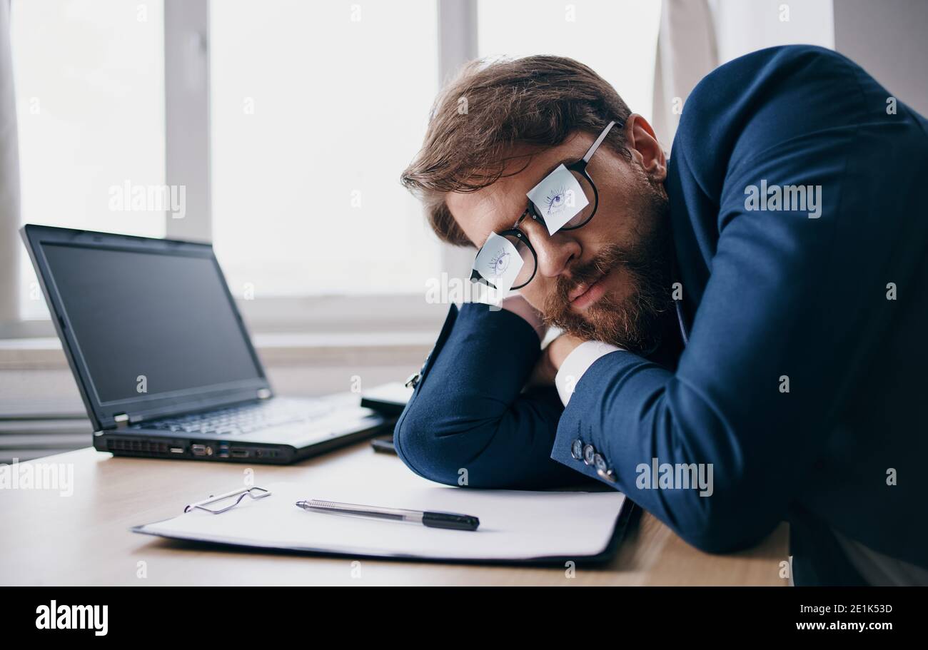 Business man sleeping at work wearing glasses with sheets of paper ...