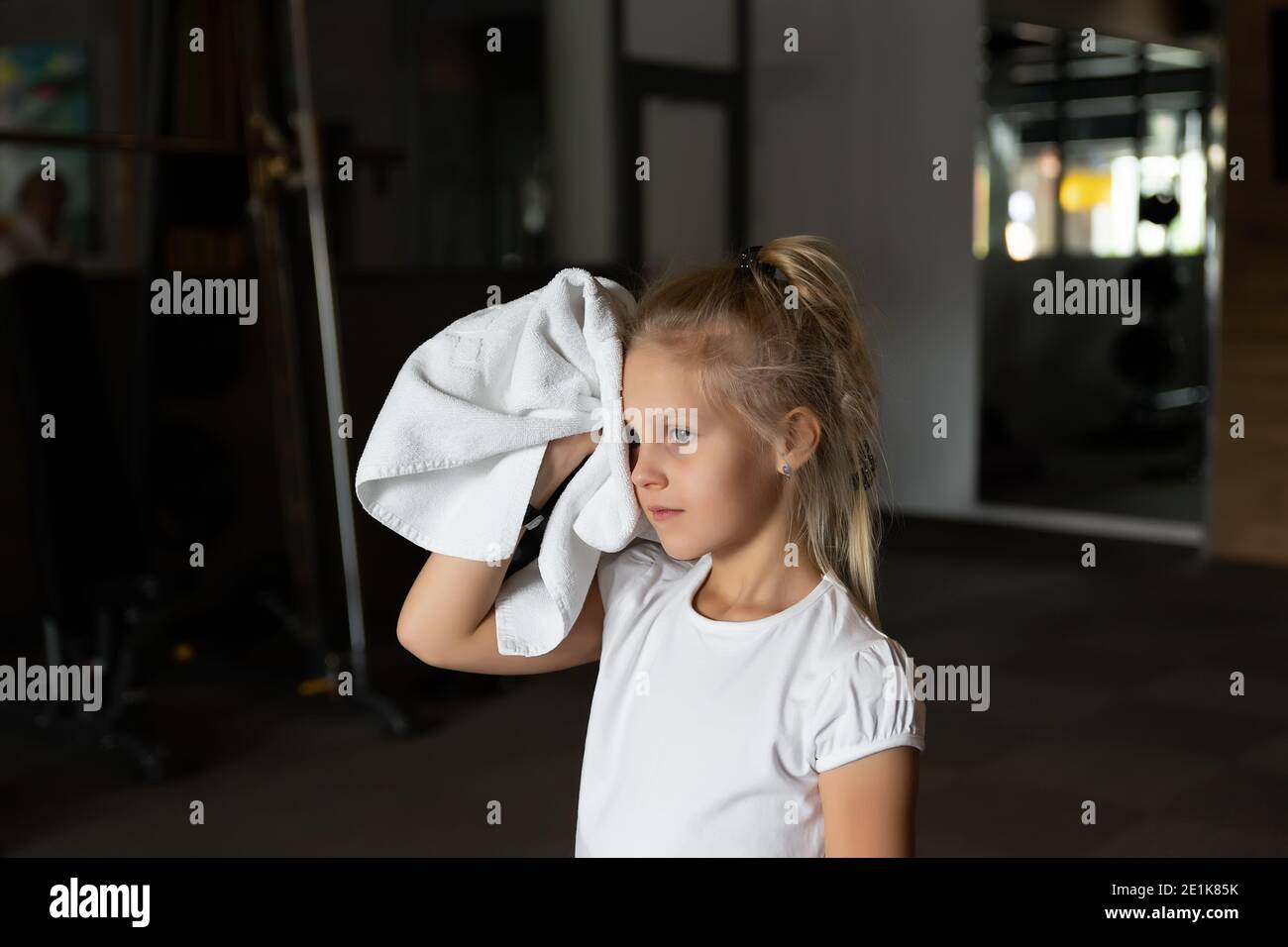 Little cute adorable caucasian blond girl doing finess exercise wiping ...