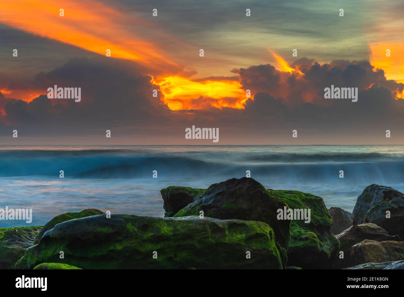 High clouds drift over a cloud bank on the horizon, sun rays streak ...
