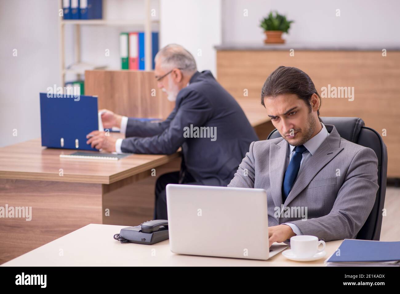 Old male boss and young male assistant in the office Stock Photo - Alamy