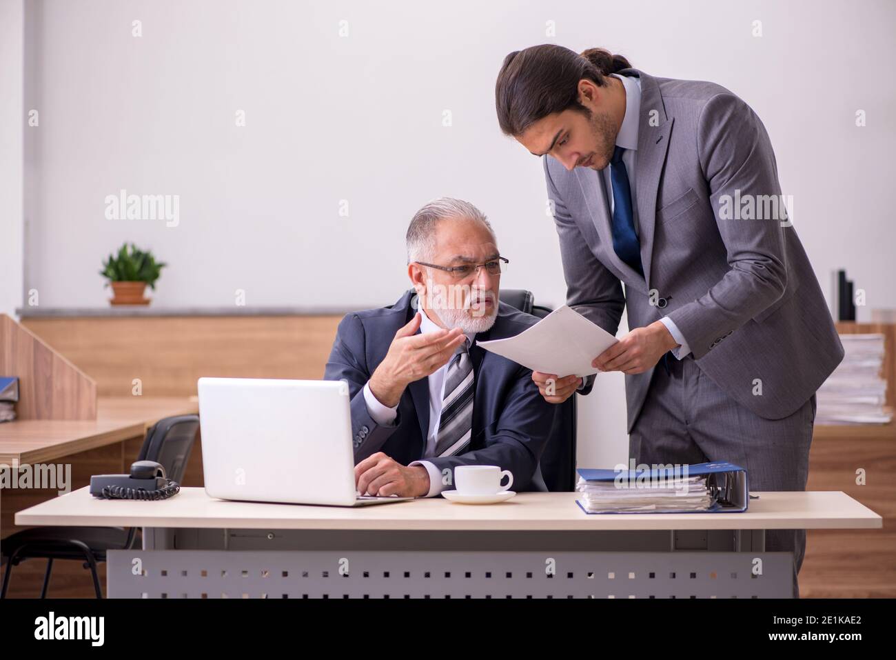 Old male boss and young male assistant in the office Stock Photo - Alamy
