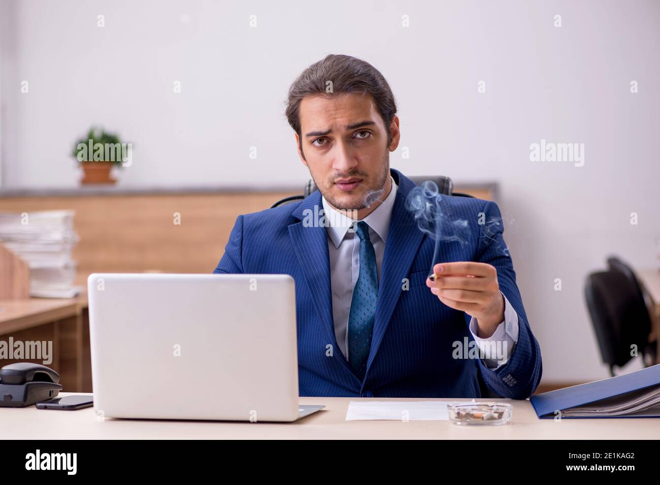 Young man employee smoking cigarettes in the office Stock Photo - Alamy