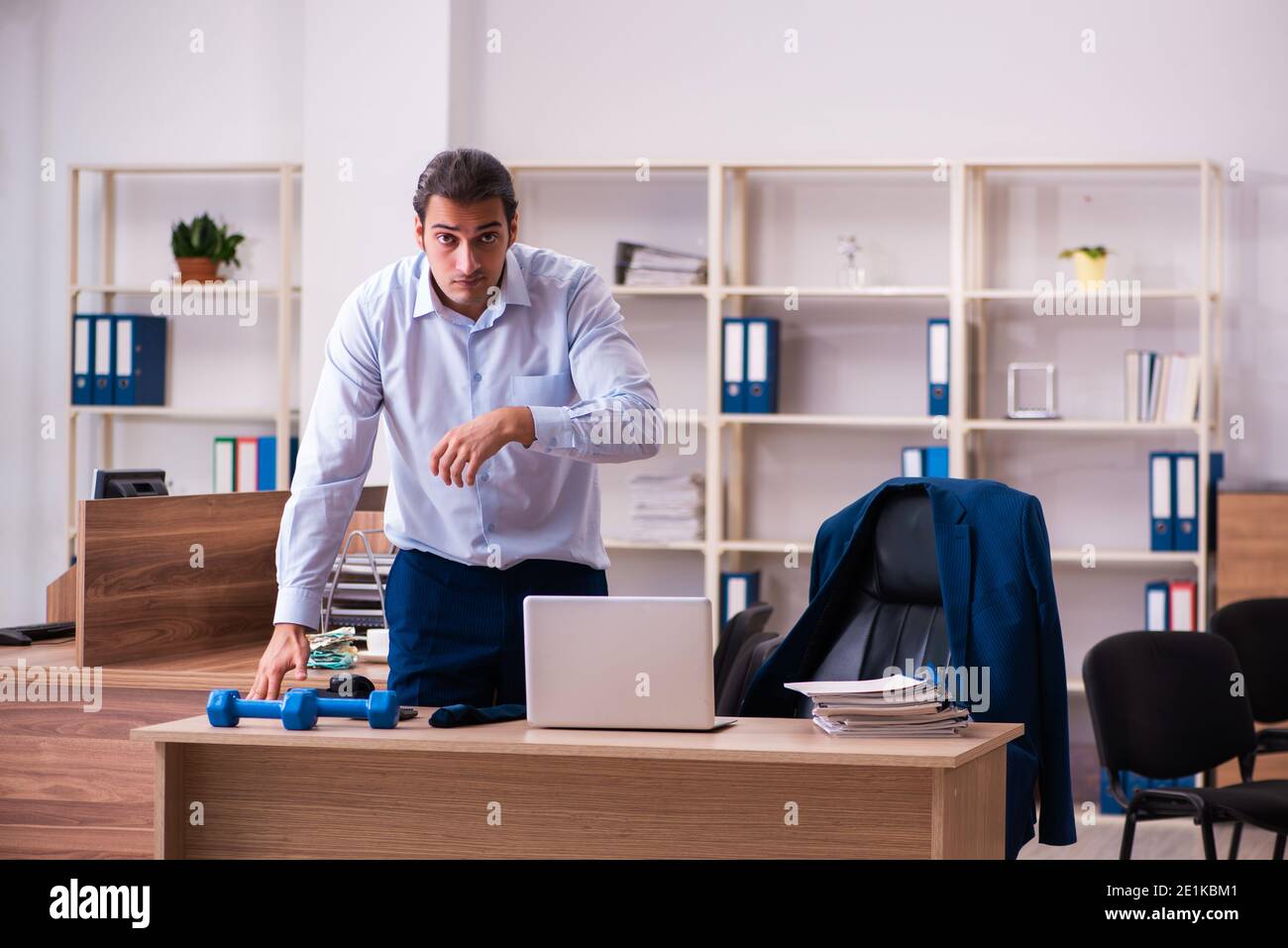 Young employee doing physical exercises at workplace Stock Photo - Alamy