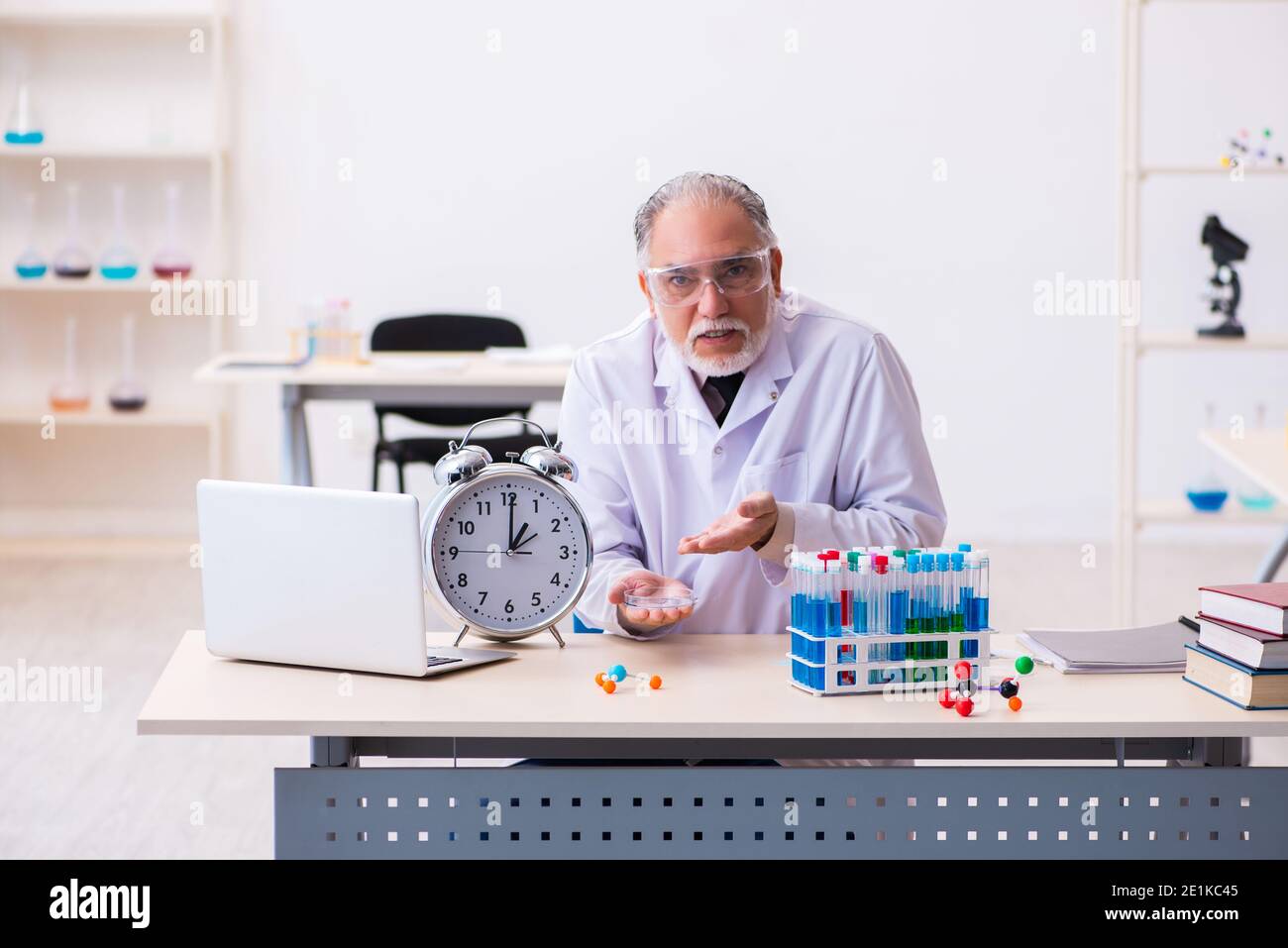 Senior male chemist in time management concept Stock Photo - Alamy