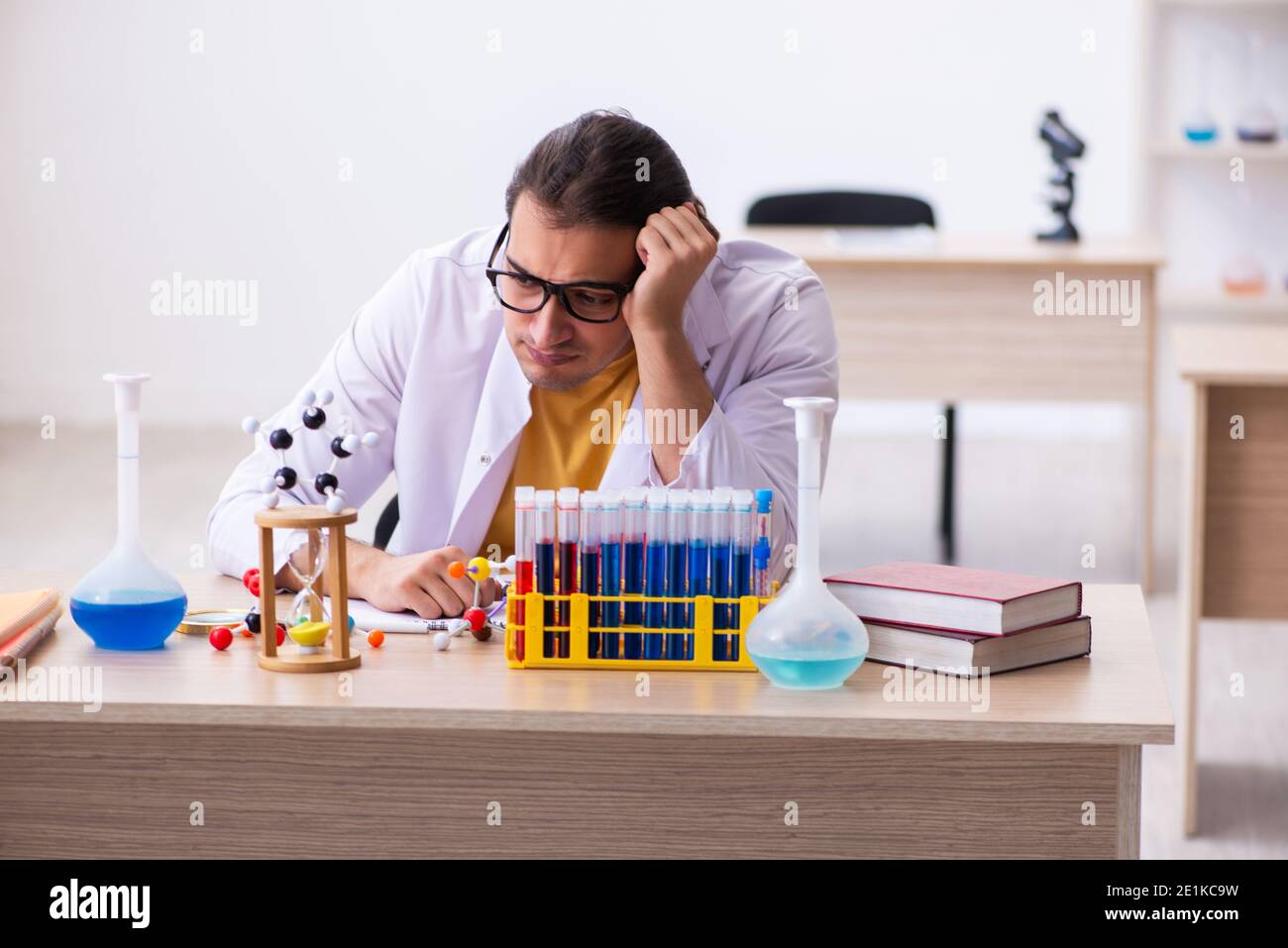 Young chemist in time management concept Stock Photo - Alamy