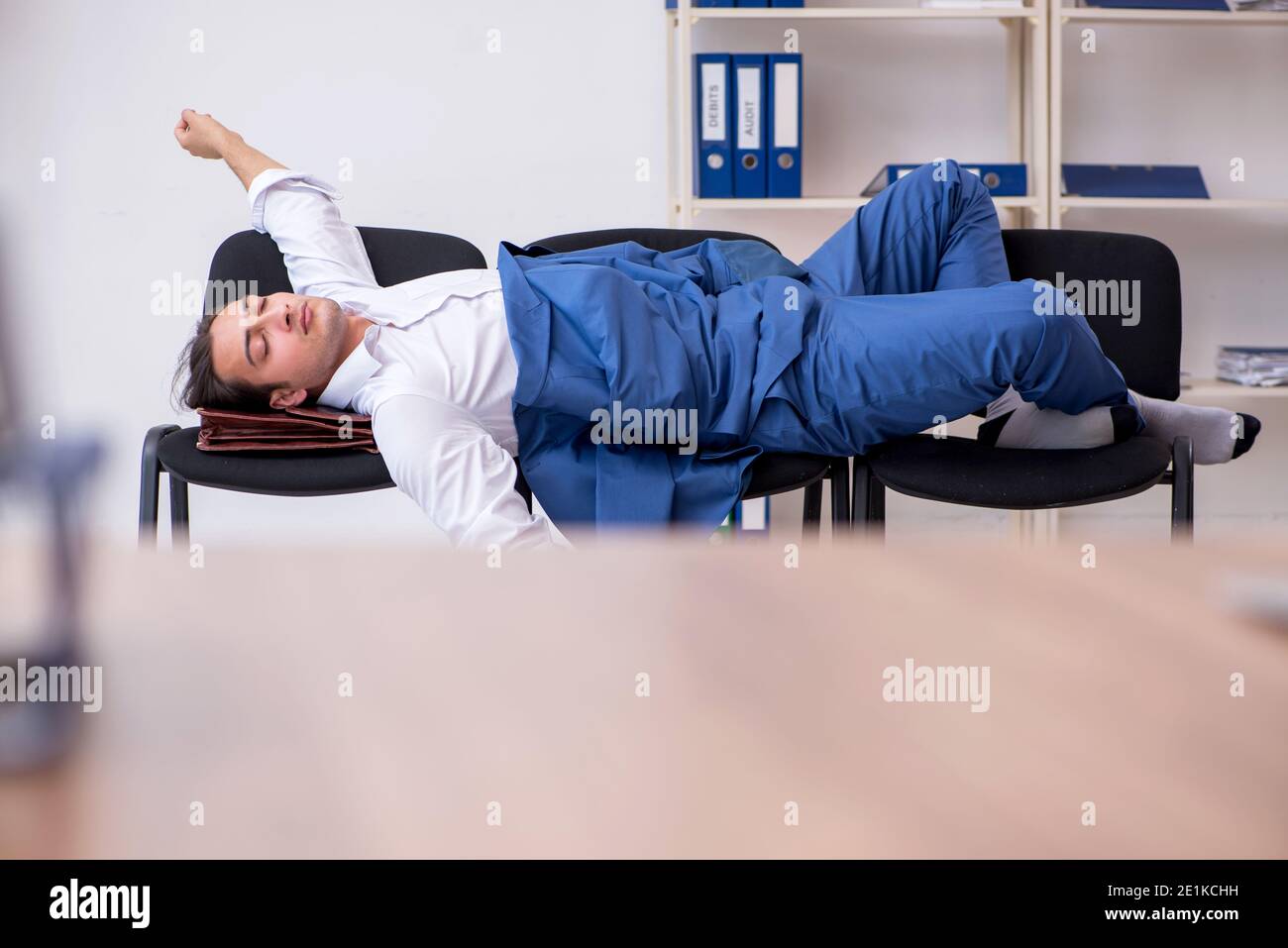 Young employee sleeping in the office on chairs Stock Photo - Alamy