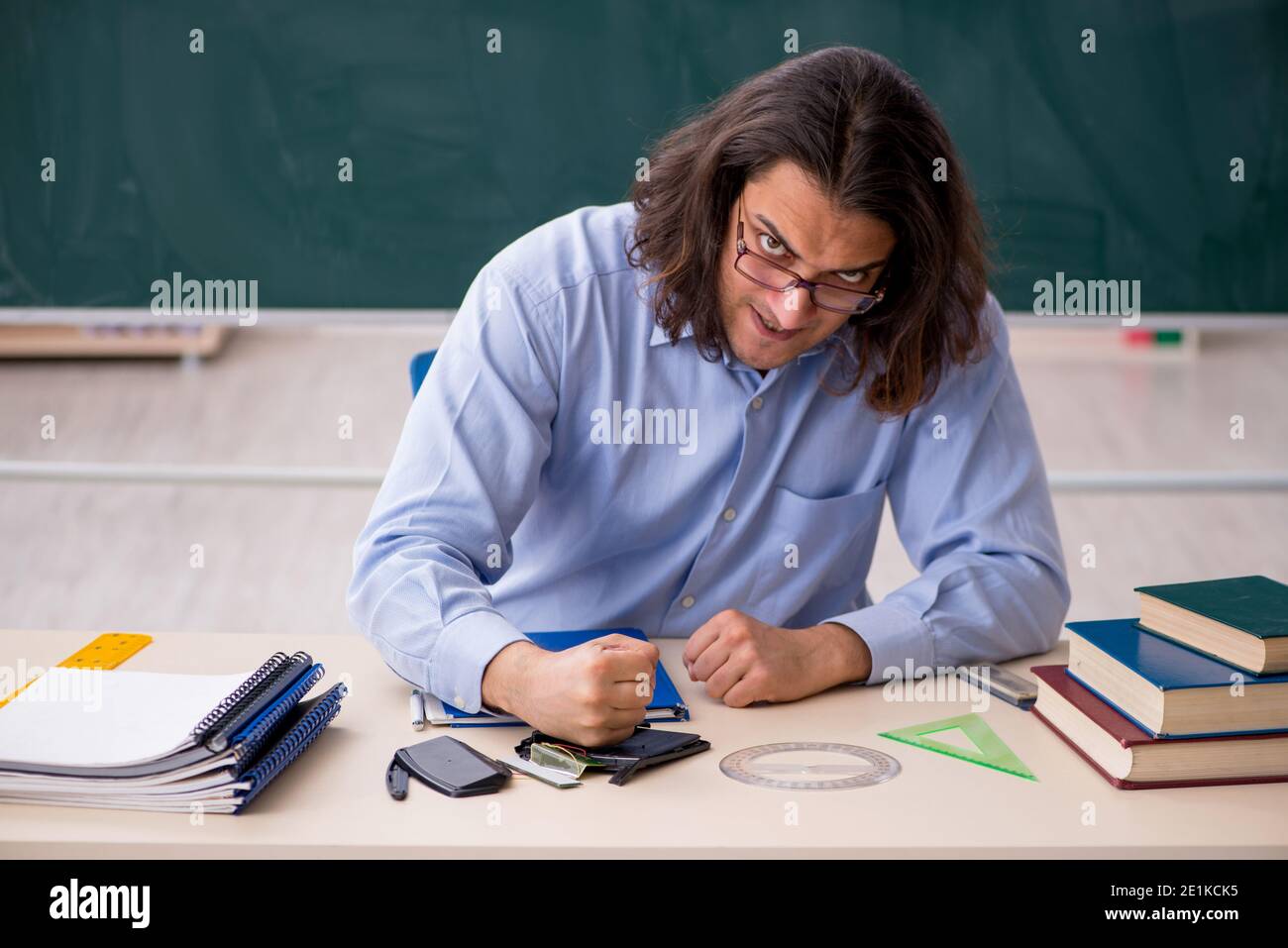 Young teacher in front of green board Stock Photo - Alamy