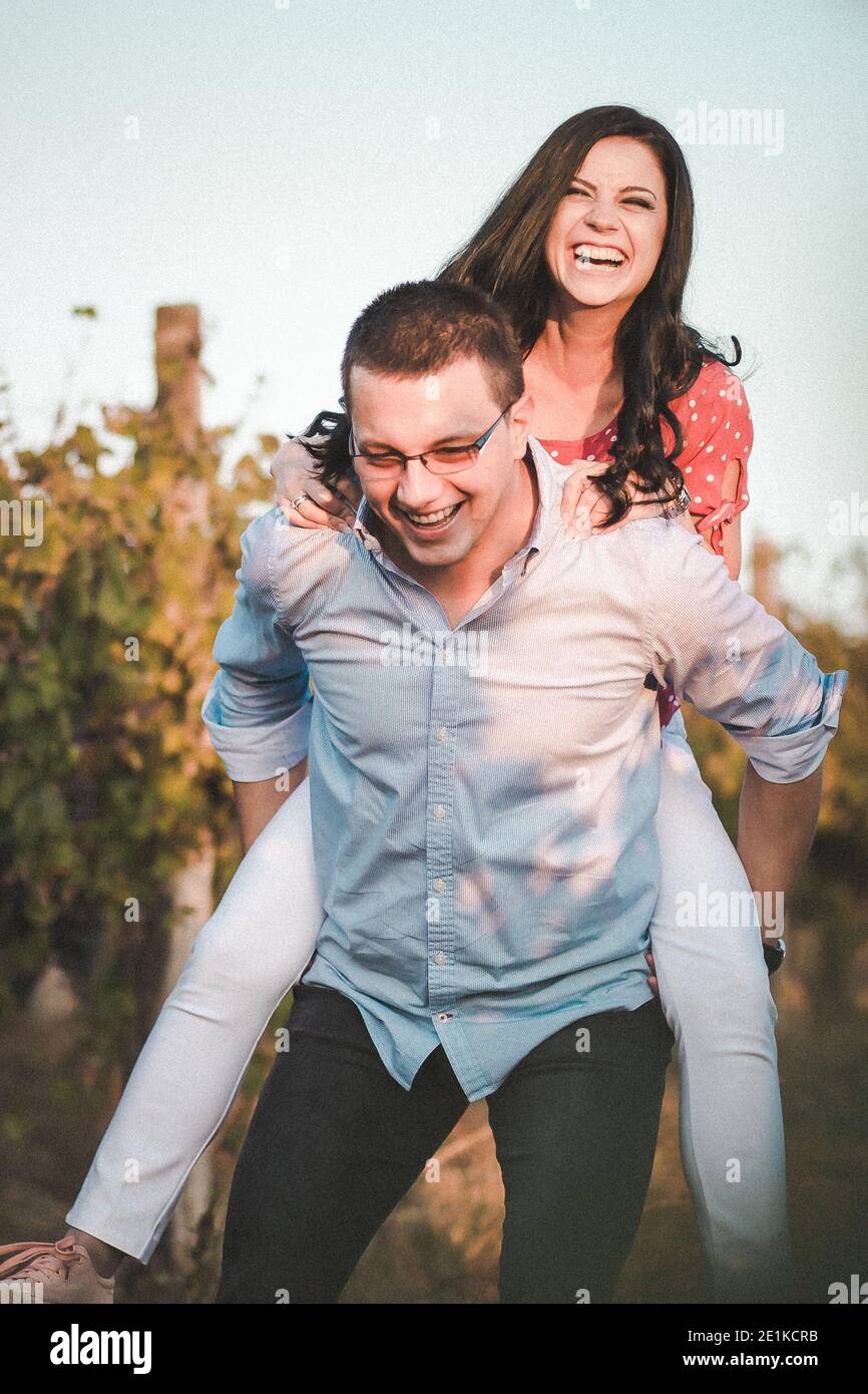 Outdoor portrait of a young couple, boyfriend carrying girlfriend on ...