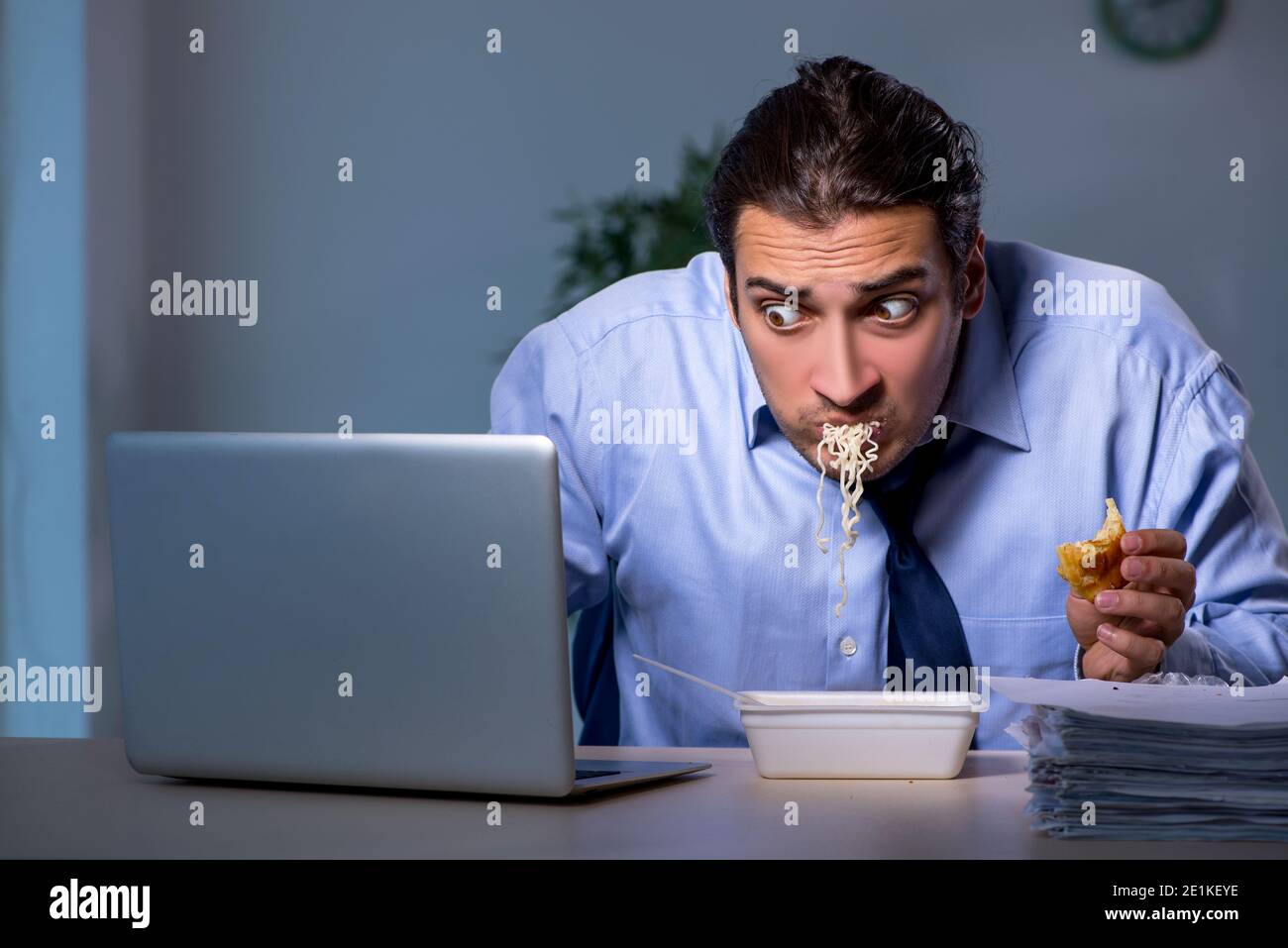 Hungry employee working late in office Stock Photo - Alamy