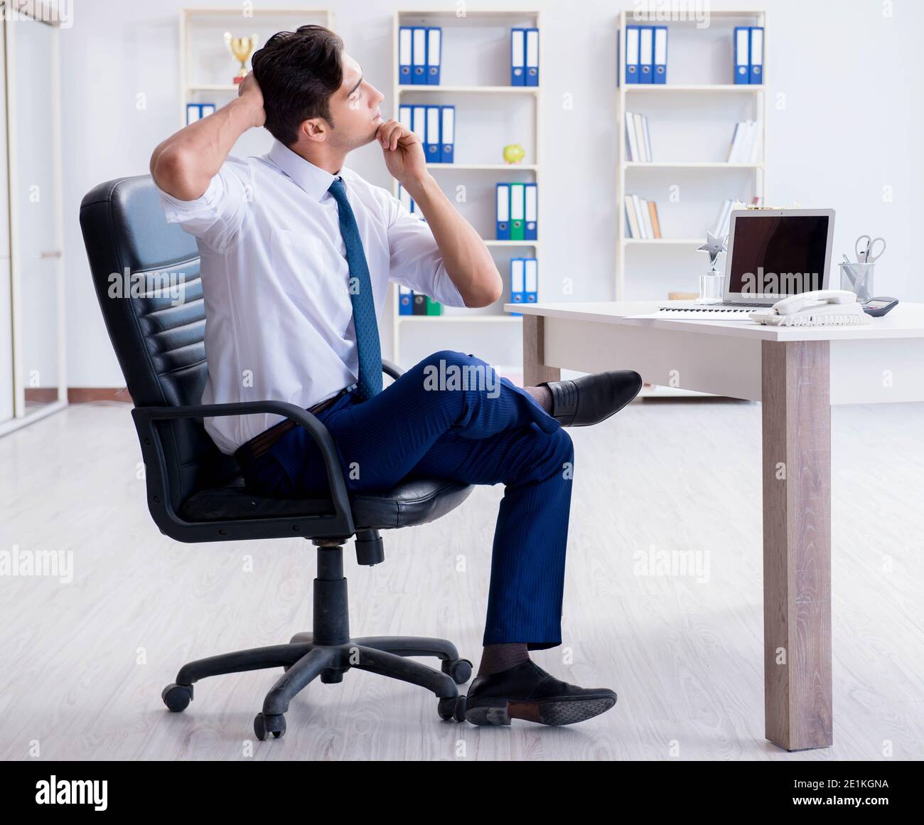 The young businessman doing sports stretching at workplace Stock Photo ...