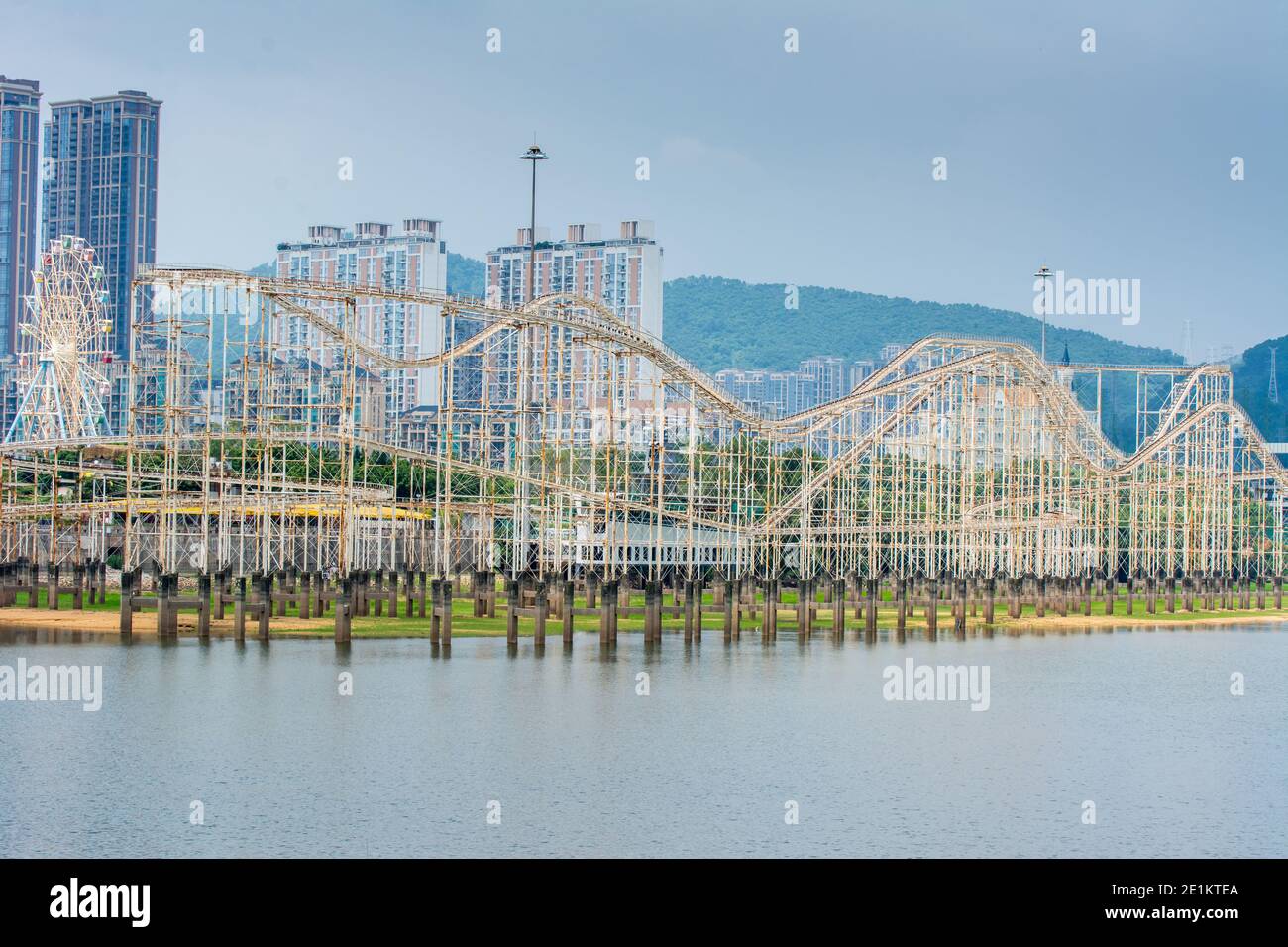 Roller coaster steel structure built above a lake with background of ...