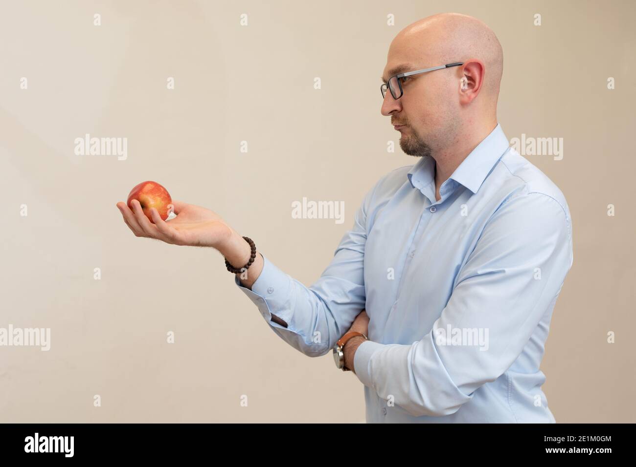 handsome adult bald man holds red apple over light background Stock ...