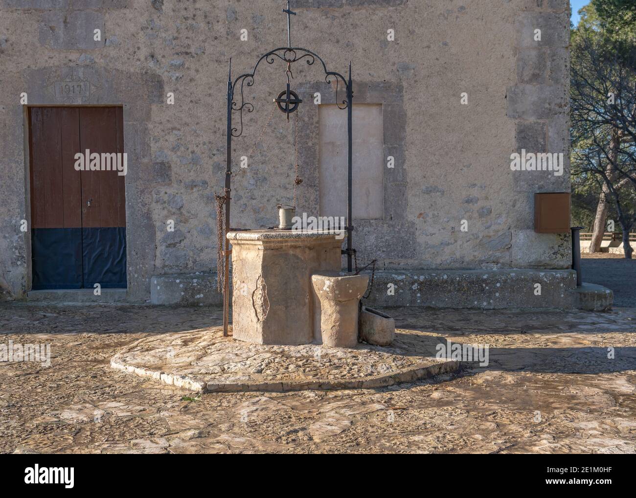 Metal bucket on an old stone well closed with a metal lid on a sunny ...