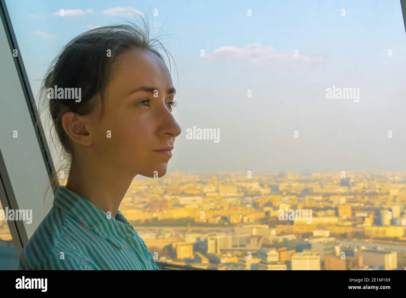 Woman looking at cityscape through window of skyscraper - sightseeing ...