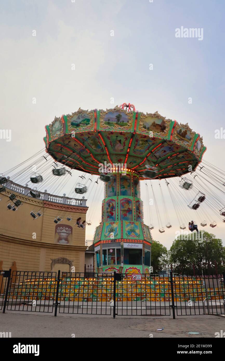 People riding the swings at Prater amusement park on a spring evening ...