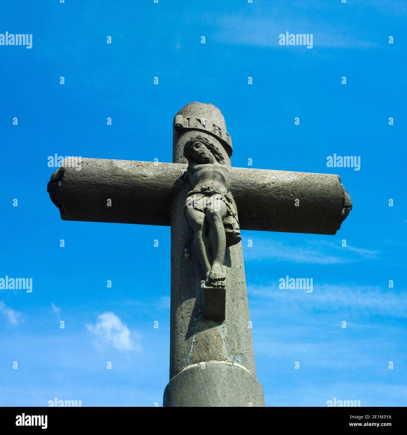Historic stone cross featuring a figure surrounded by a clear blue sky ...