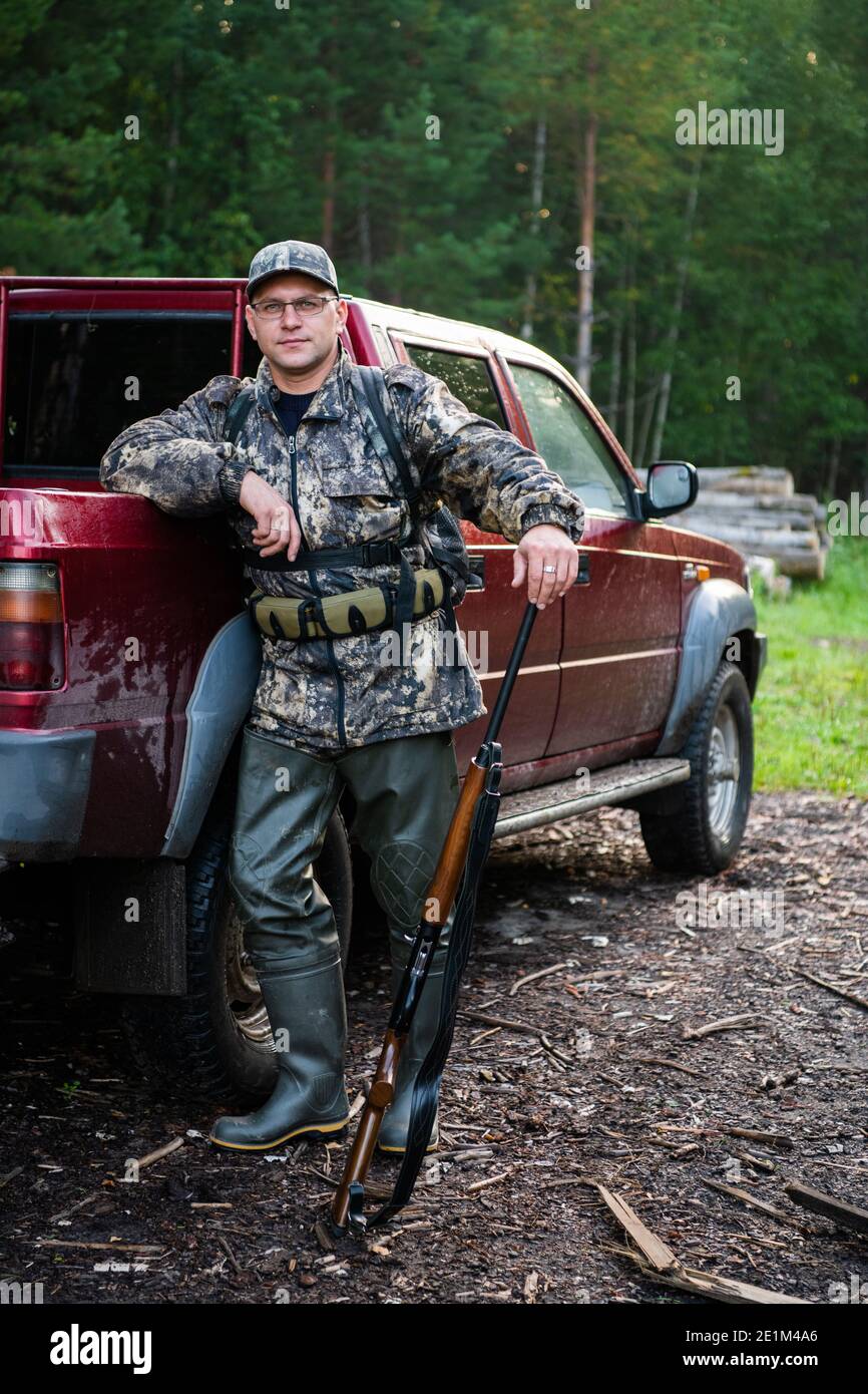 Man hunter standing with shotgun rifle near his car outdoor preparing ...