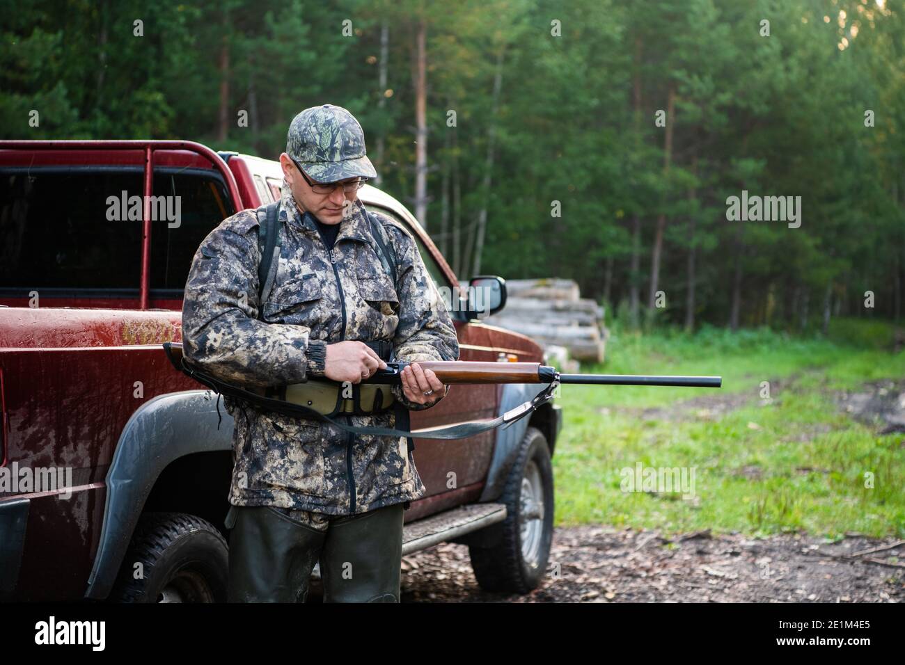Man hunter standing with shotgun rifle near his car outdoor preparing ...