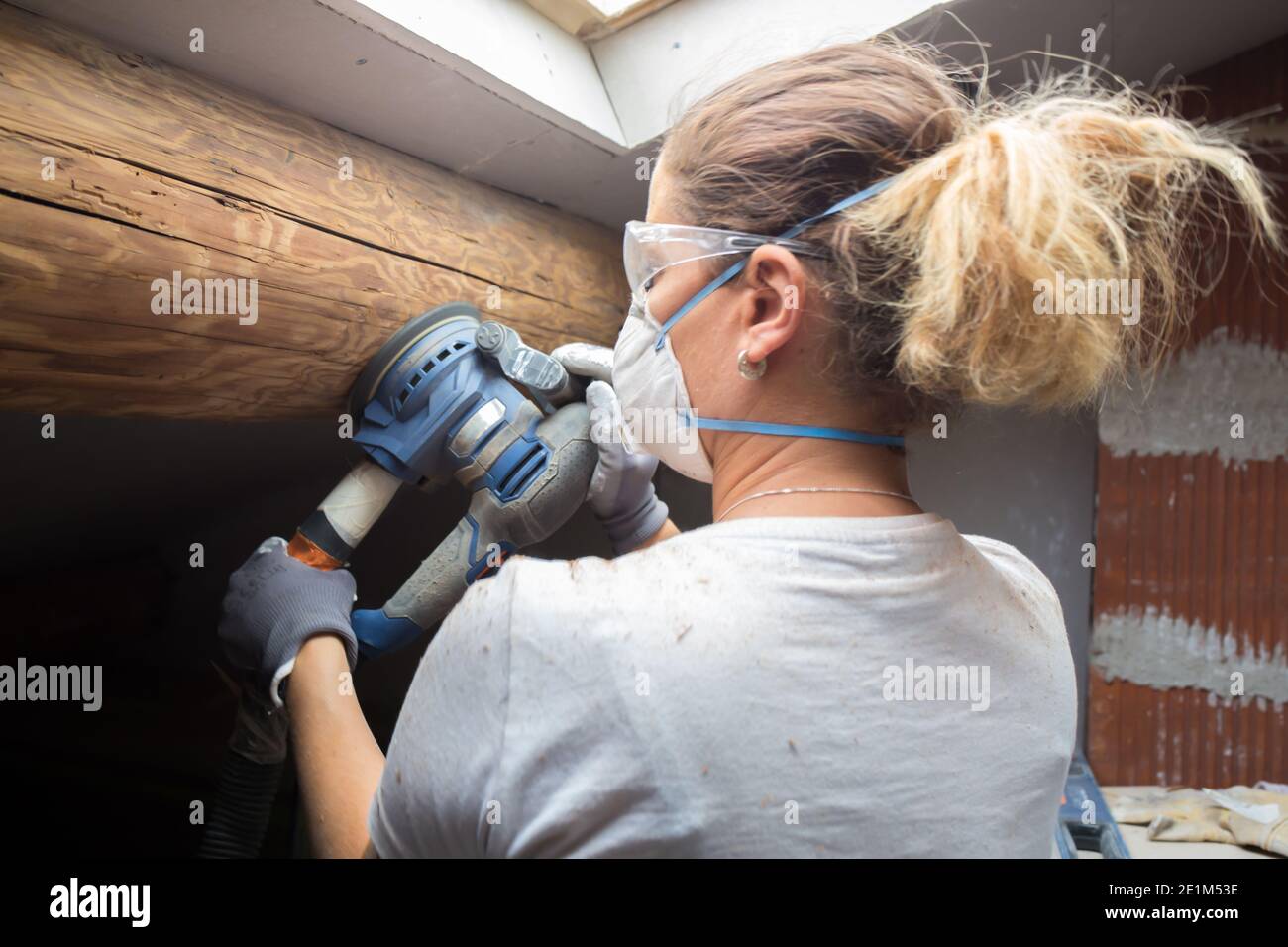 Woman Renovating Attic House - Sanding beam Stock Photo - Alamy