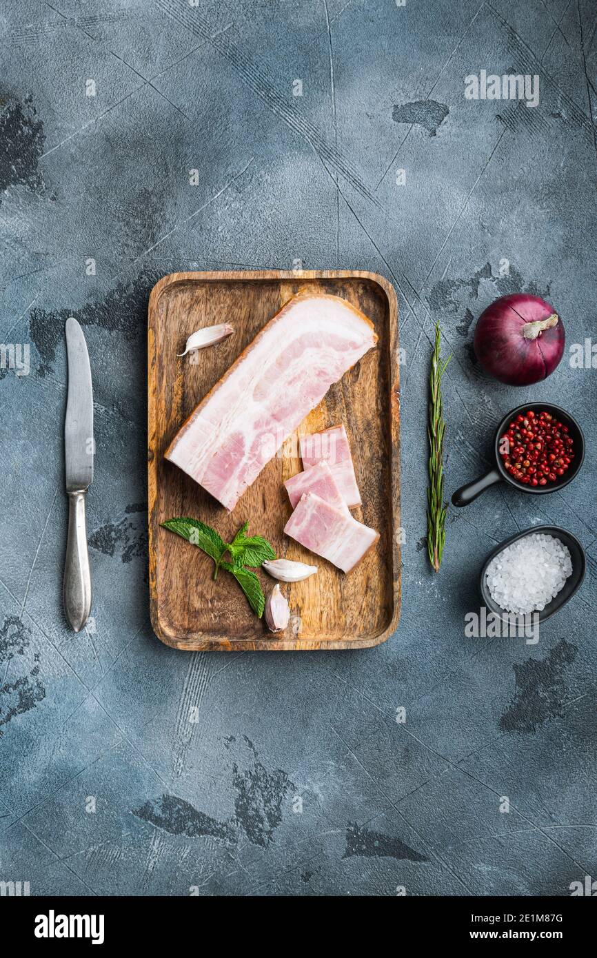 Bacon pancetta cut and sliced with herbs on grey textured background ...