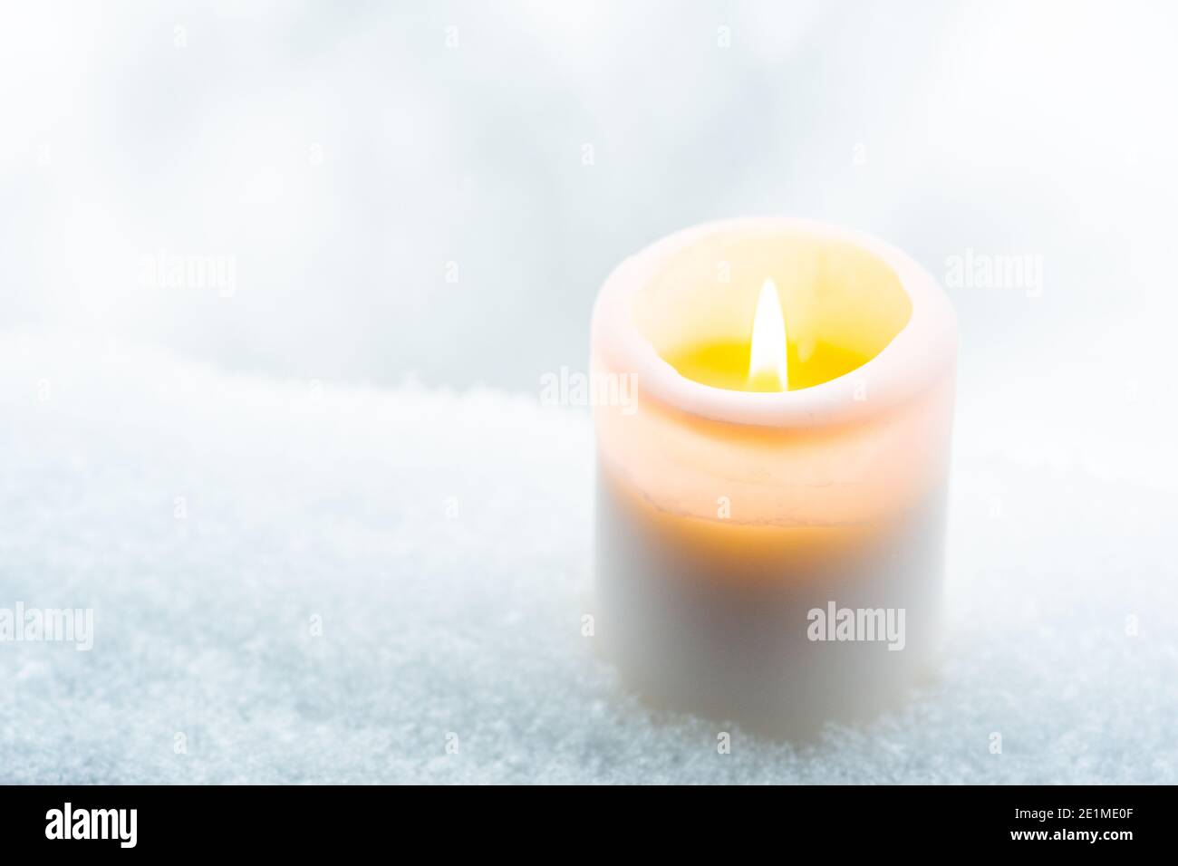 Candle burning on the snow snow or snowy surface, winter background ...