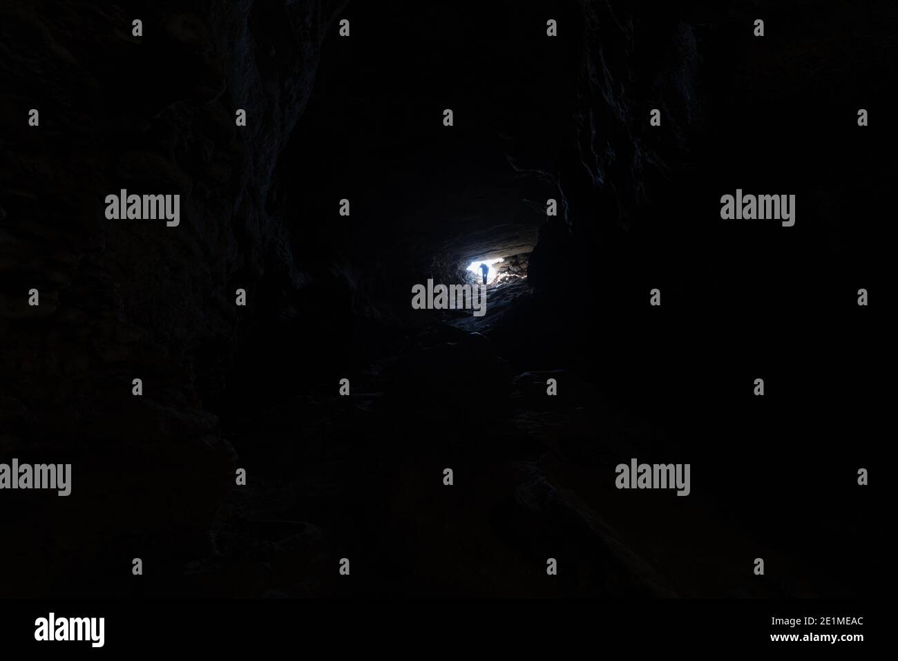 Rear view of unrecognizable person leaving the cave Stock Photo - Alamy
