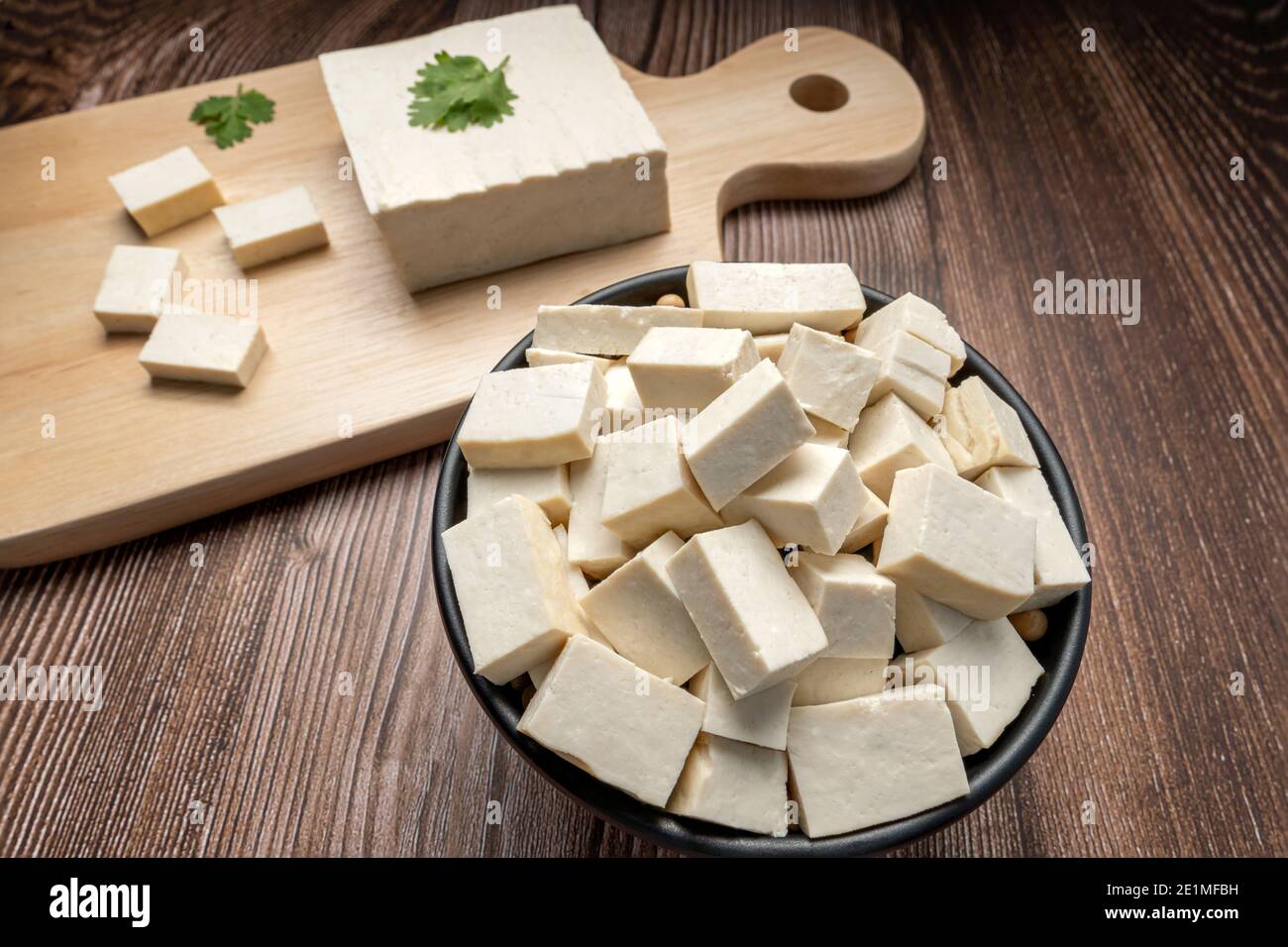 Whole fresh tofu and Diced Tofu in black bowl. full depth of field ...