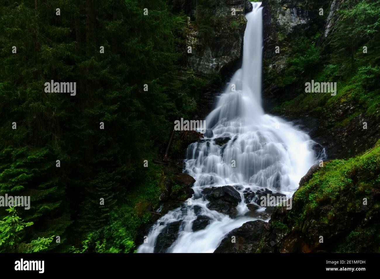 beautiful soft large waterfall between green plants and rocks in the ...