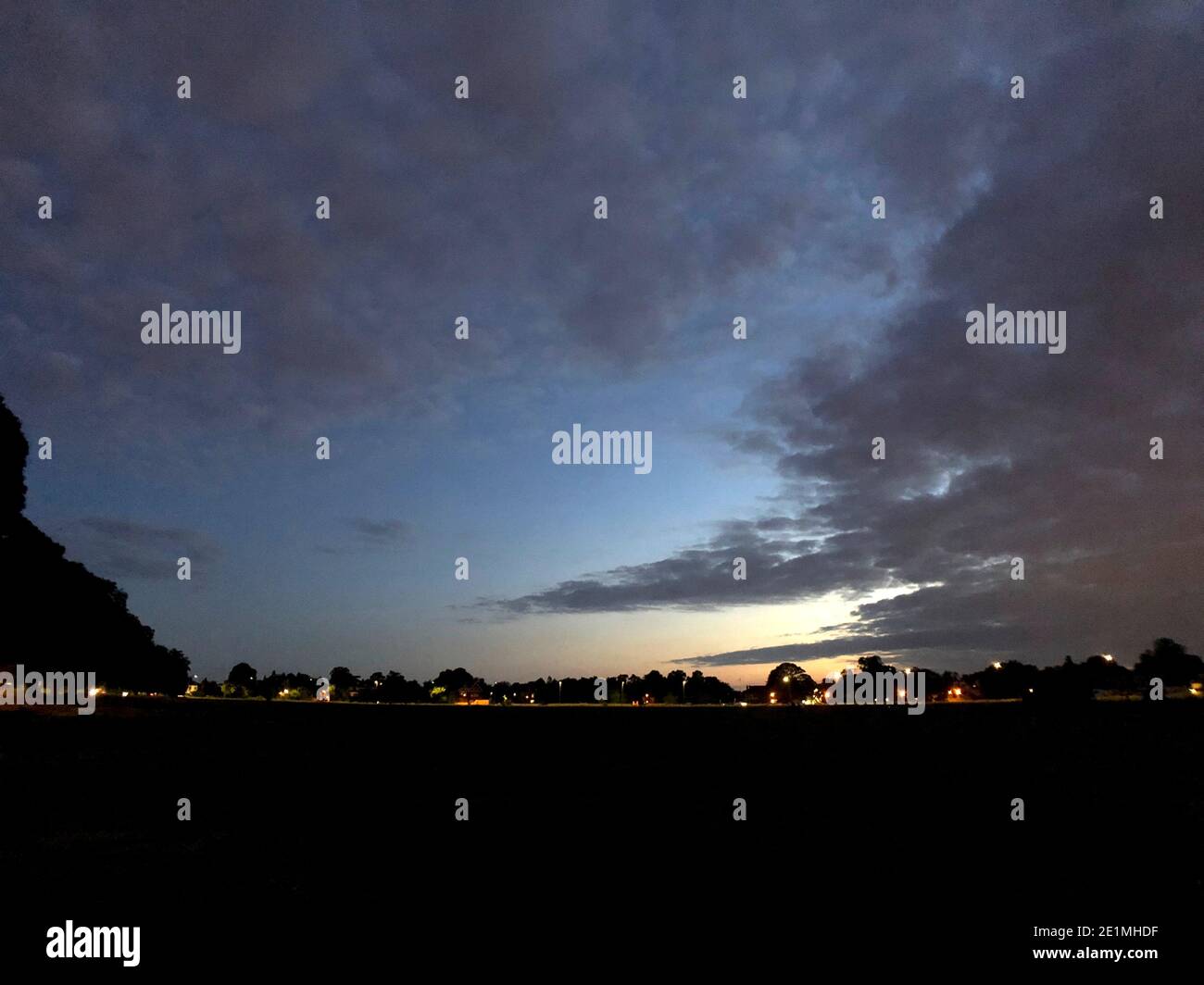 Night sky over distant houses with light big clouds dark blue sky ...